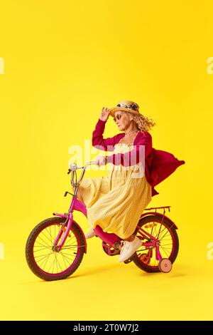 Trendy woman in cardigan and straw hat holding ripe apple while sitting ...