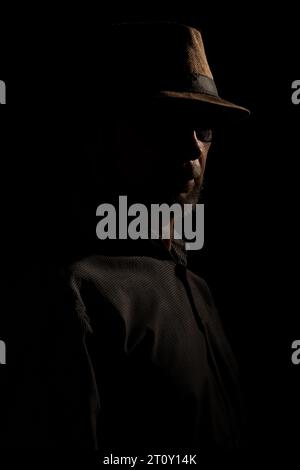 Discreet portrait of detective man with hat in darkness. Dark room art ...