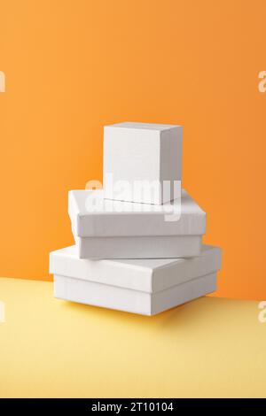 Three closed white jewelry boxes on yellow background Stock Photo - Alamy