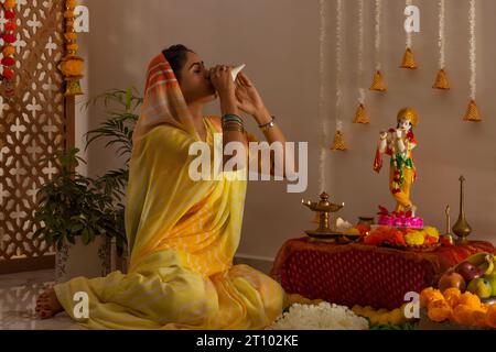 Woman playing conch while worshipping Lord Krishna on the occasion of ...