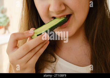Kid bites cucumber, close-up, unrecognizable face. Girl eating cucumber ...