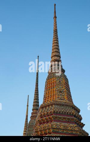 Three ornate temple spires against a blue sky. The spires are decorated ...