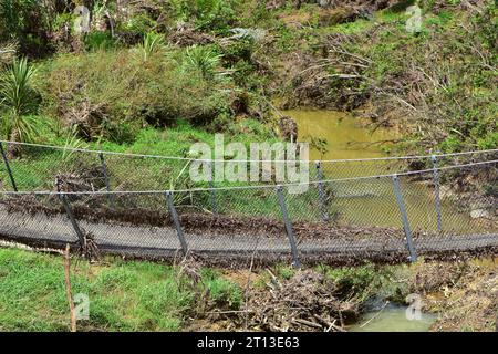Twisted suspension pedestrian bridge after flood with broken floor ...