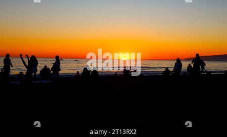 Suggestive Sunset on the beach with silhouettes of people watching ...