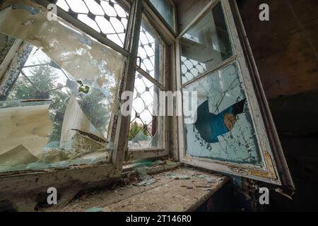 Opened window with shattered glass inside dark room of abandoned ...