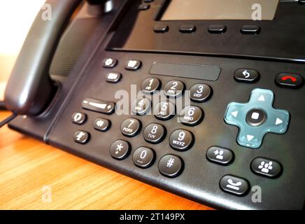 The black desktop push-button telephone. IP phone on desk in office ...