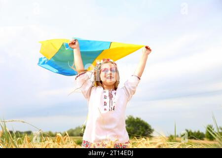 Girl carries fluttering blue and yellow flag of Ukraine in field ...