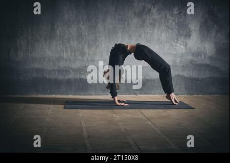 Beautiful woman practices backbend yoga asana Urdhva Dhanurasana ...