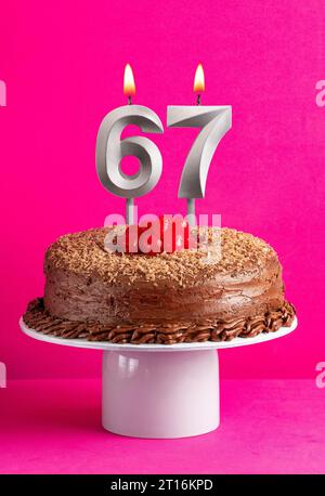 Pink number 67 birthday candle on white background Stock Photo - Alamy