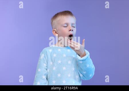 Sleepy boy yawning on purple background. Insomnia problem Stock Photo ...