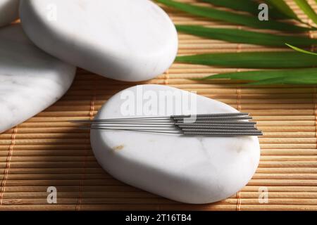 Stones with acupuncture needles on bamboo mat Stock Photo - Alamy