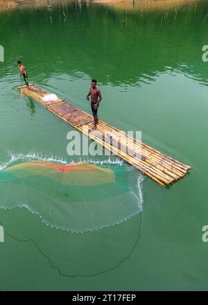 Indigenous men catching fish using net Stock Photo - Alamy