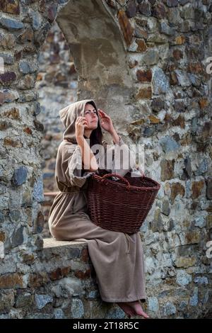 Woman in medieval peasant dress checking her food basket in the cellars ...