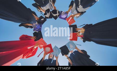 College graduates make a circle shape out of their colorful hats Stock ...
