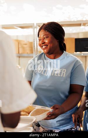 Friendly black woman giving free, hot meals to homeless people at a ...