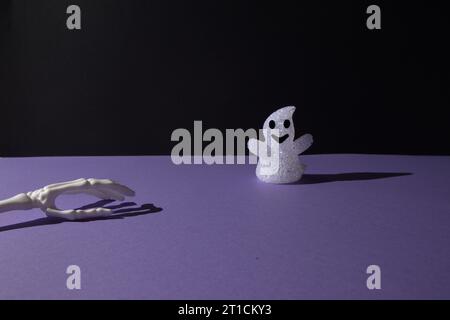 A ghost decoration for Helloween and hand bones on purple black ...