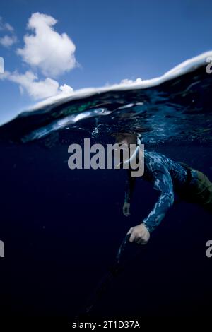 A vertical shot of a scuba diver swimming underwater around a shipwreck ...