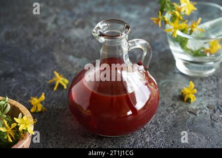 Red St. John's wort oil in a glass jar with fresh Hypericum flowers ...