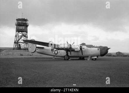 A USAAF Consolidated B-24J Liberator is parked by the control tower at ...