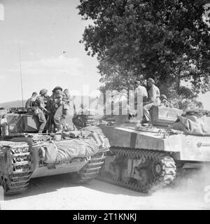 A Sherman tank carrying infantry passes through roadblocks as British ...