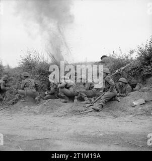 Troops of the East Yorkshire Regiment take cover behind a bank as an ...