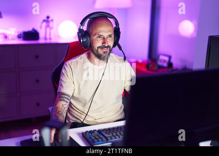 Young bald man streamer playing video game using computer at gaming ...