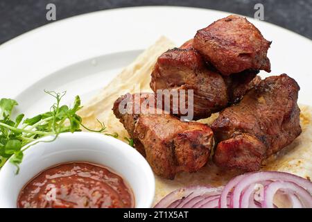 Fried shish kebab with lavash, sauce, microgreen and onion, on a white ...