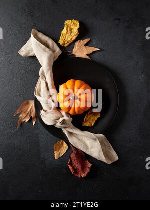 Autumn table setting, fallen maple leaves and pumpkin with cutlery on a ...