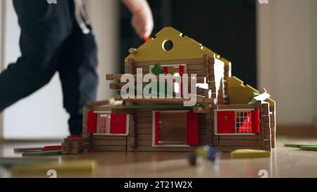 Child destroying house construction miniature. Kid kicking model wood ...