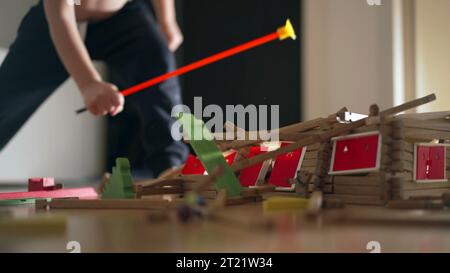 Child destroying house construction miniature. Kid kicking model wood ...