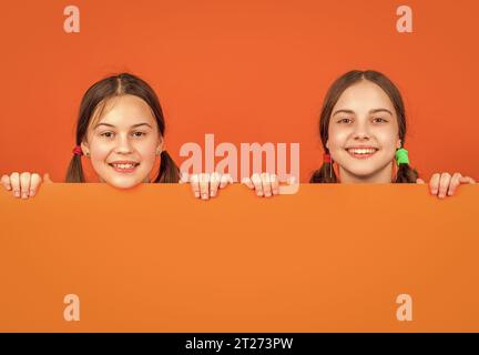 happy children behind blank orange paper with copy space for ...