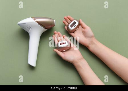 Female hands with modern photoepilator attachments on green background ...
