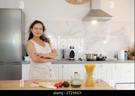 Pretty housewife smiling cutely at camera, holding a mold with rolled ...
