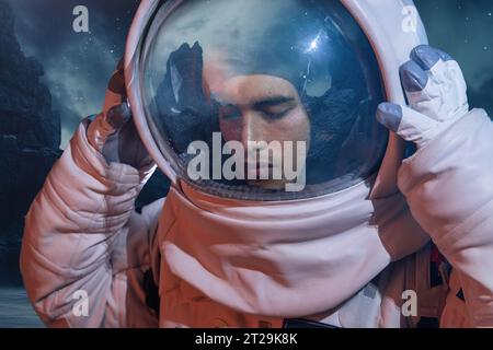 Male astronaut in spacesuit touching virtual reality goggles over head ...