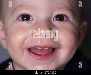 Face of a smiling baby boy with snot from his nose. Runny nose and ...
