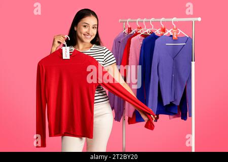 Smiling woman shopping for new clothes in a modern fashion boutique ...
