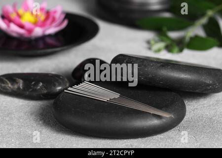 Stones with acupuncture needles on grey textured table, top view. Space ...