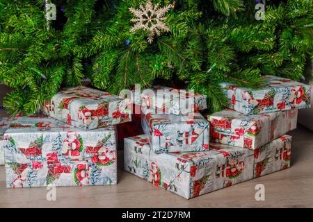 Many gift boxes under Christmas tree indoors, closeup. Space for text ...