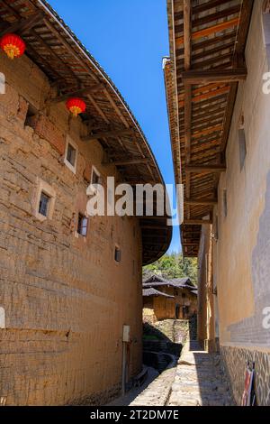 The path between two Tulou mud buildings with a blue sky, Fujian, China ...