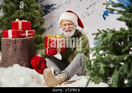 Santa Claus with gifts sitting next to a Christmas tree Stock Photo - Alamy
