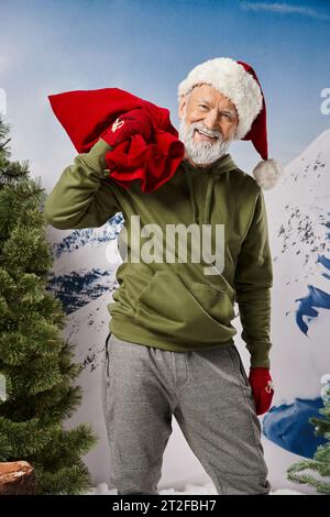 smiling man with red christmas present in studio. santa man at ...