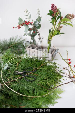 Process of making beautiful Christmas wreath with fir branches on table ...
