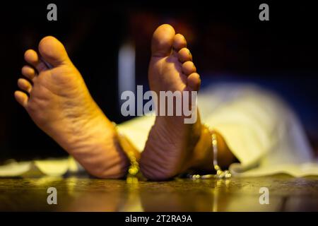 Feet of an Indian or Asian female dead body lying on floor in a dark ...