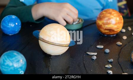 Close-up view of painted planets being assembled for a detailed solar ...
