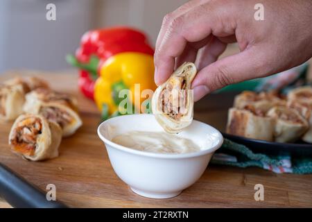 hand holding shawarma piece and dip it in mayonnaise or garlic tahini ...