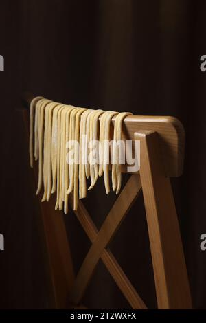 Homemade pasta drying on chair against dark background Stock Photo - Alamy
