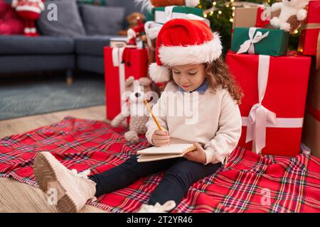 Adorable blonde toddler writing on notebook lying on bed at bedroom ...