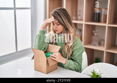 Young woman unboxing package with worried expression at home Stock ...