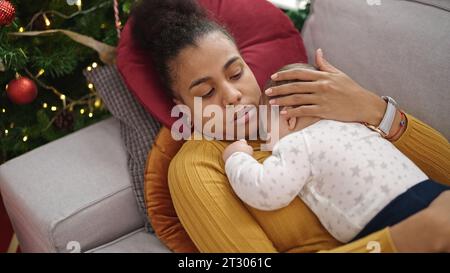 Adorable hispanic baby holding christmas decoration ball sitting on ...