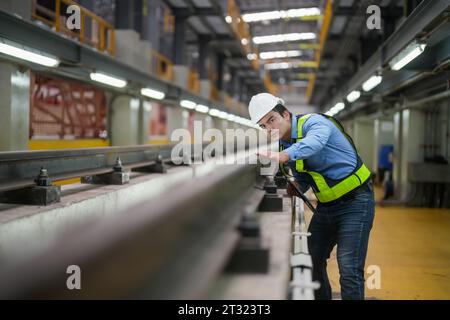 Portrait of apprentice under train in railway engineering facility ...